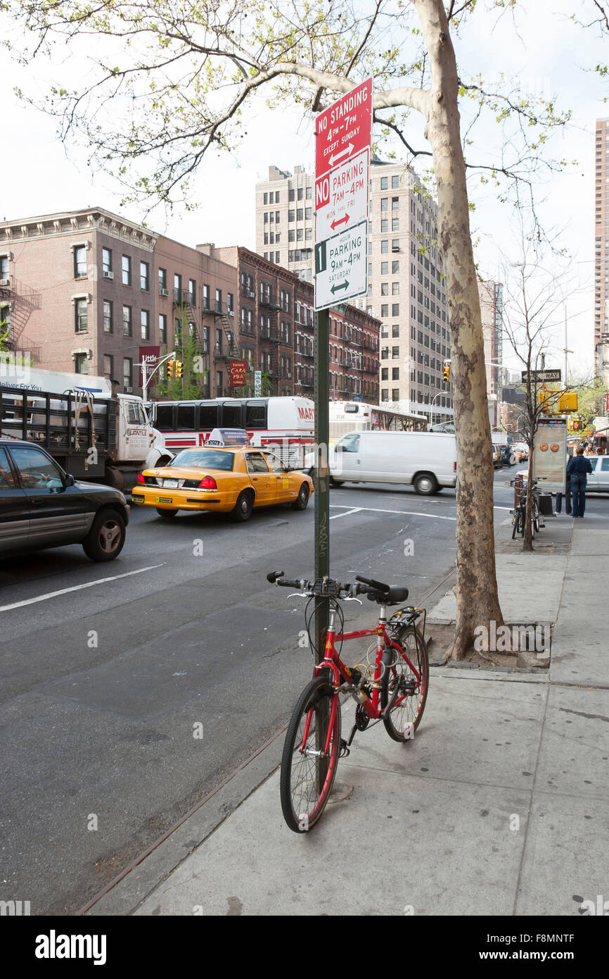 A bike chained to a street sign pole next to cars driving in Midtown ...