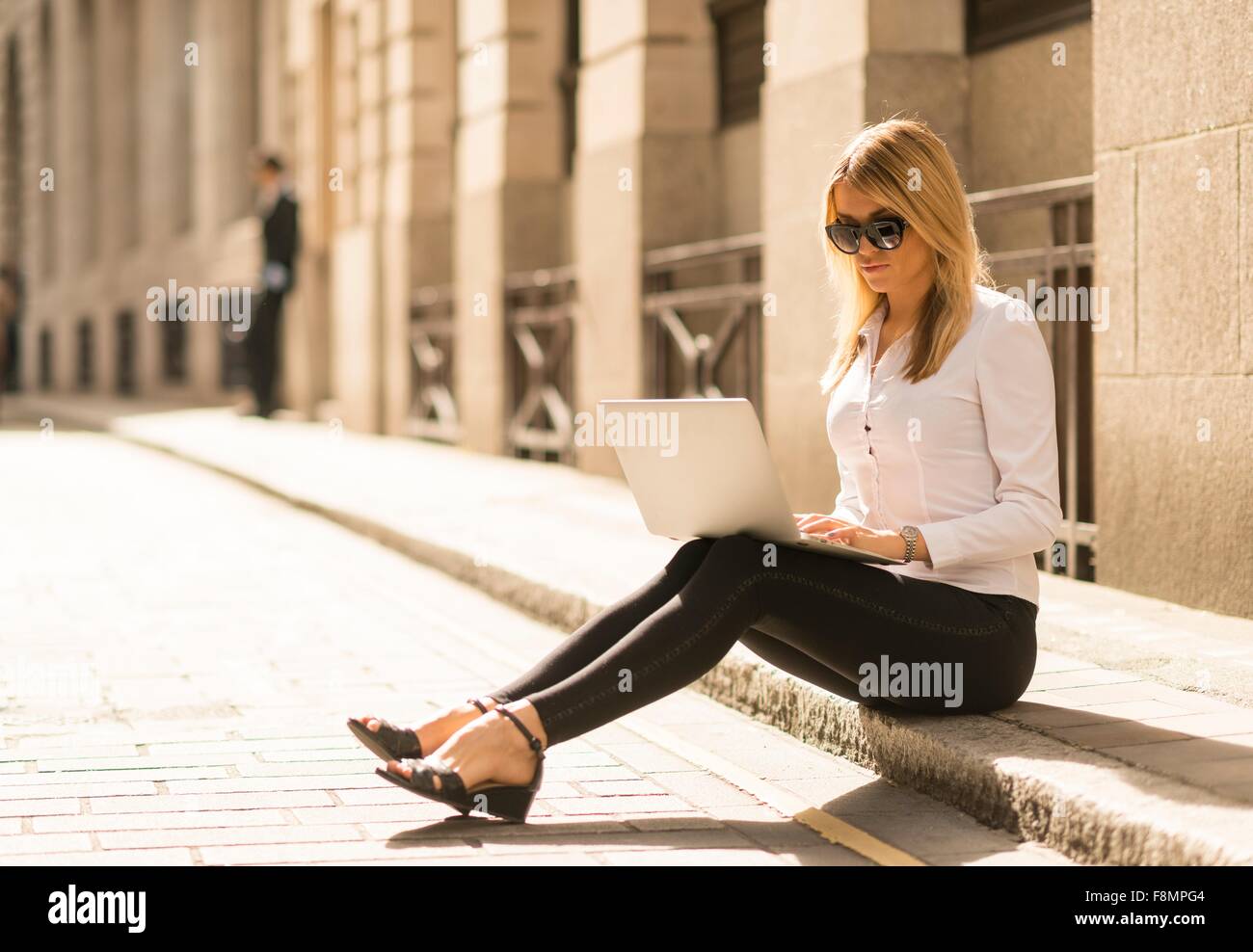 Businesswoman using laptop on kerb, London, UK Stock Photo - Alamy