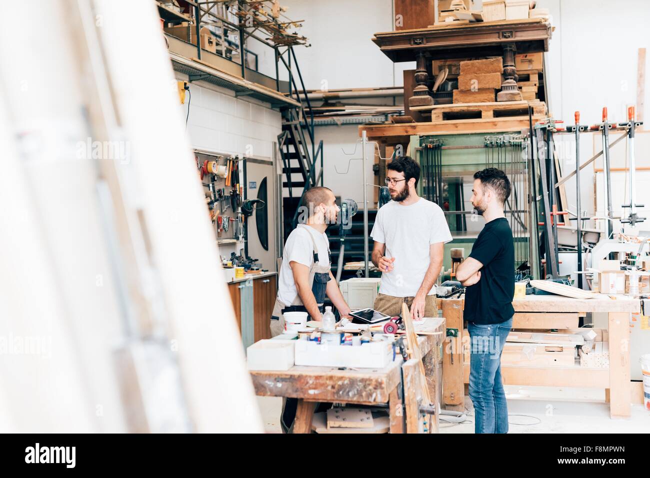 Friends standing around workbench in carpentry workshop talking Stock ...