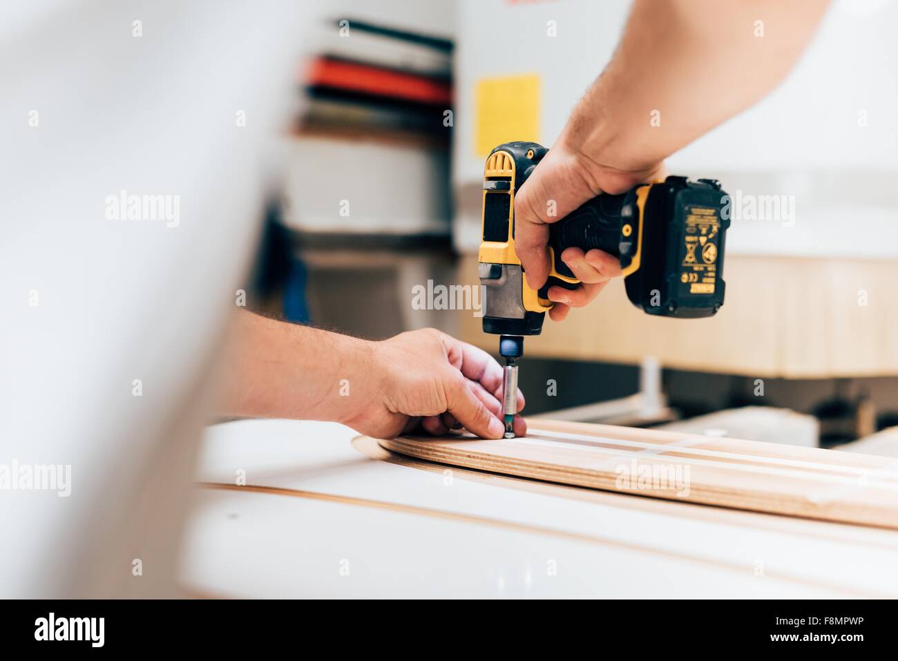 Cropped view of young man in carpentry workshop using cordless ...