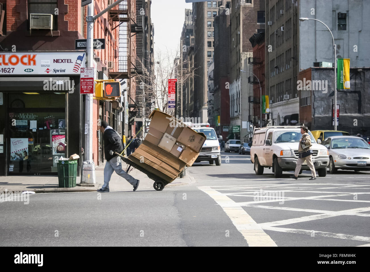 A man hauling cardboard boxes on a trolley on intersection of 9th ...