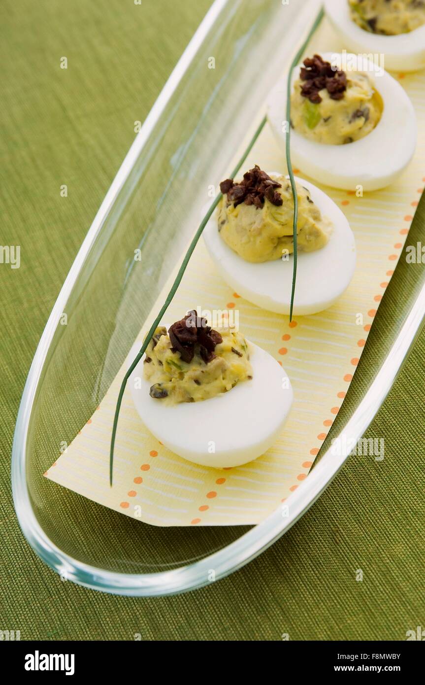 Eggs a la russe, garnished with chopped olives, on a platter Stock ...
