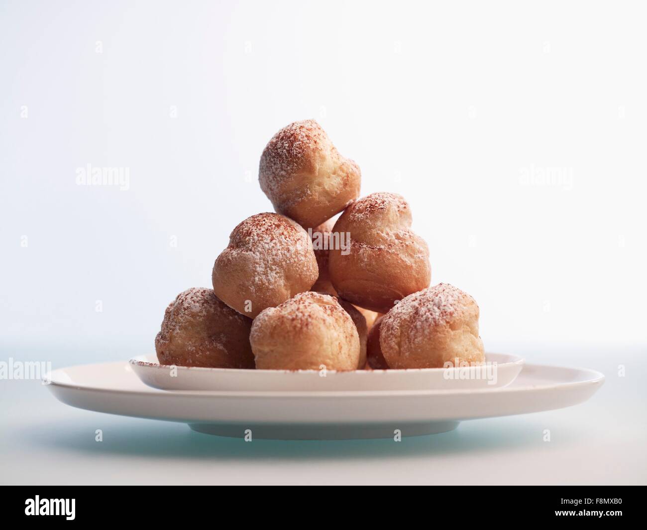A stack of profiteroles on a plate against a white background Stock ...