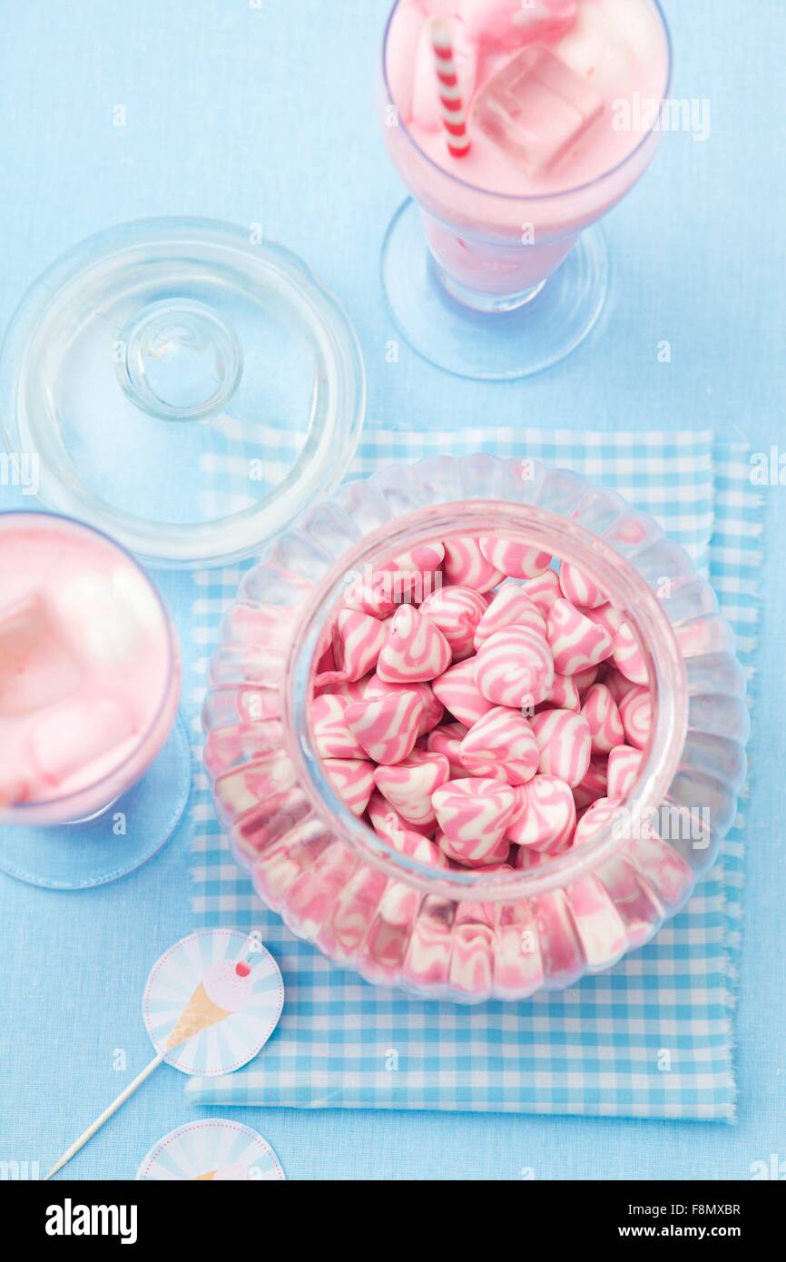 A jar of pink and white striped sweets, and a strawberry milkshake with ...
