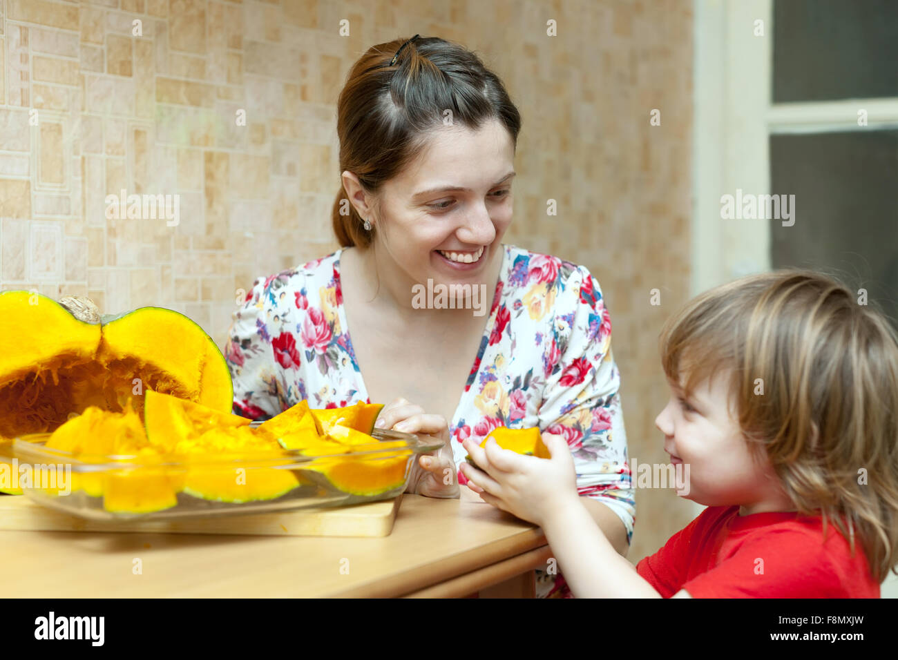 Happy mother with girl cooks pumpkin in kitchen together. Focus on ...
