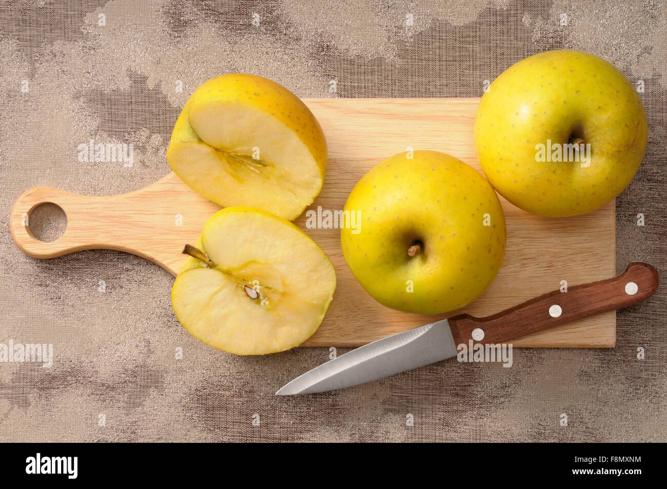 Golden Delicious apples, whole and halved, on a chopping board Stock ...