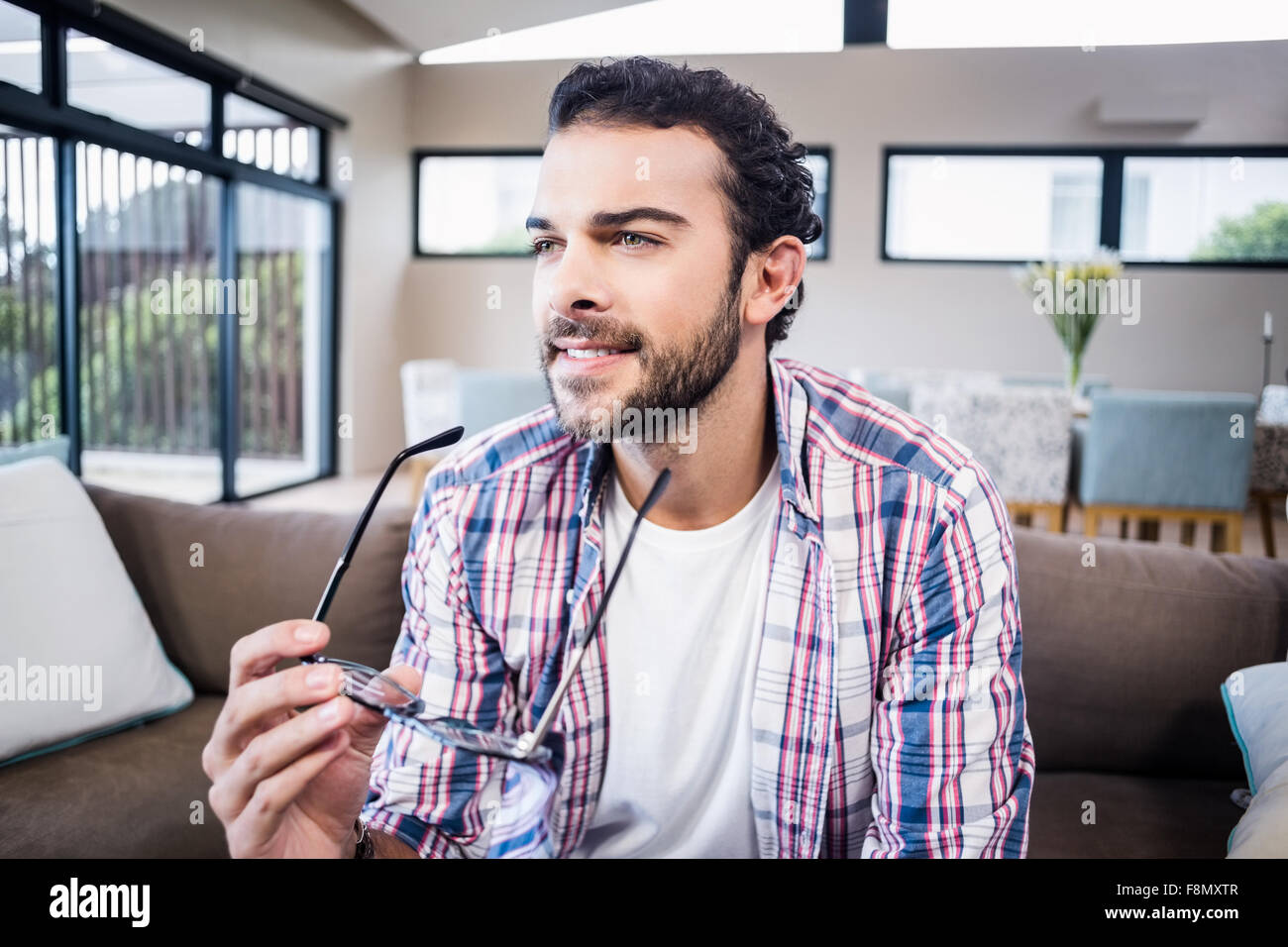 Smiling man holding glasses looking away Stock Photo - Alamy