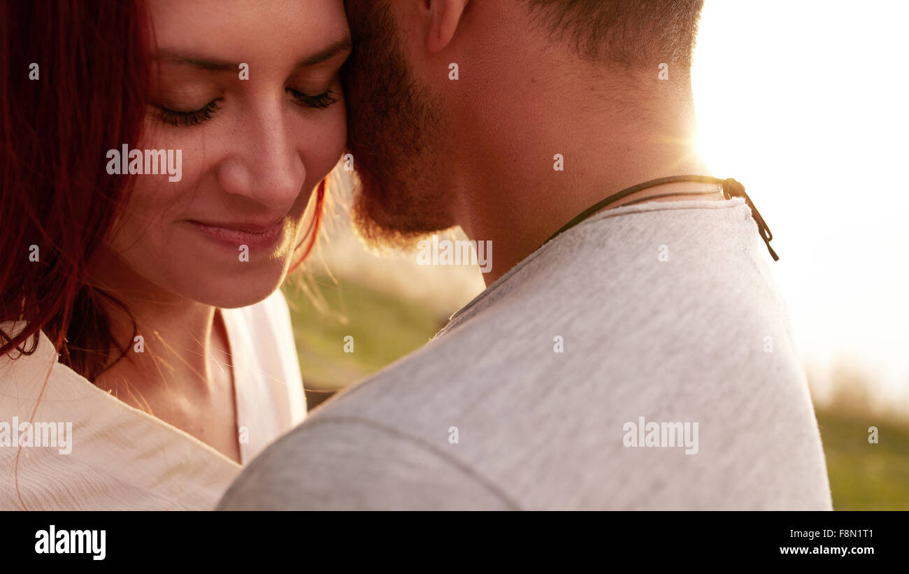 Close up shot of affectionate young woman embracing her boyfriend with her eyes closed. Romantic ...