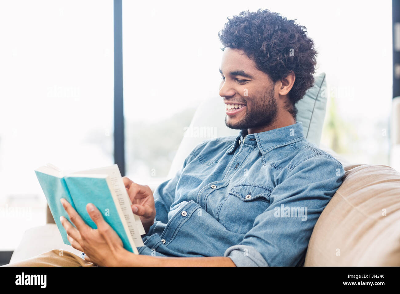 Smiling man reading book Stock Photo - Alamy