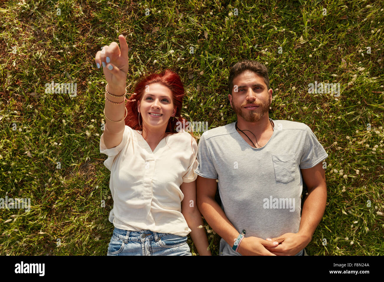 Overhead view of young man and woman lying on the grass, with woman ...
