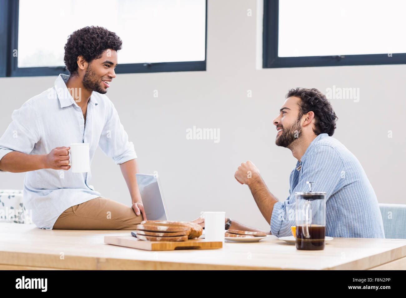 Happy gay couple using laptop and talking Stock Photo - Alamy