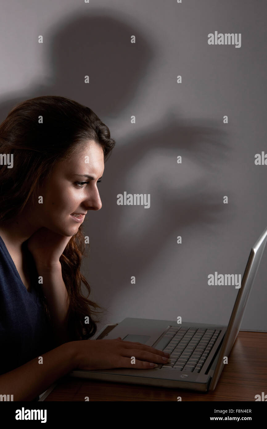 Teenage Girl Using Laptop With Menacing Shadow In Background Stock ...