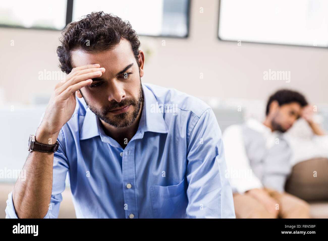 Troubled man sitting in foreground Stock Photo - Alamy