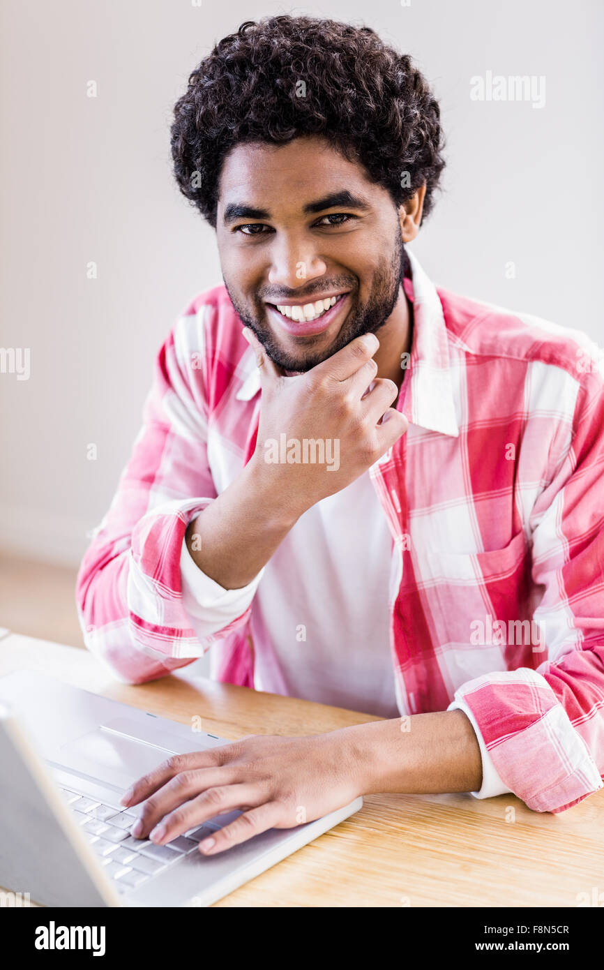 Smiling man using laptop and looking at the camera Stock Photo - Alamy