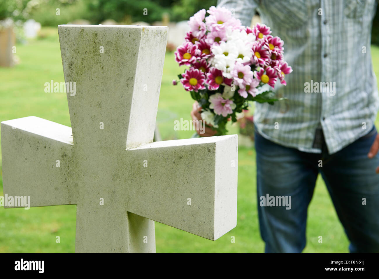 Man Placing Flowers By Headstone In Cemetery Stock Photo - Alamy