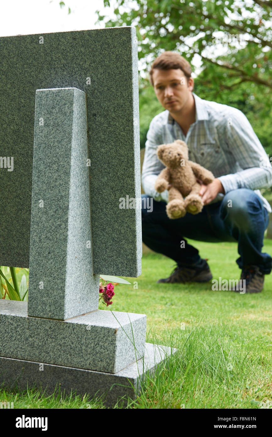 Father Placing Teddy Bear On Child's Grave In Cemetery Stock Photo - Alamy