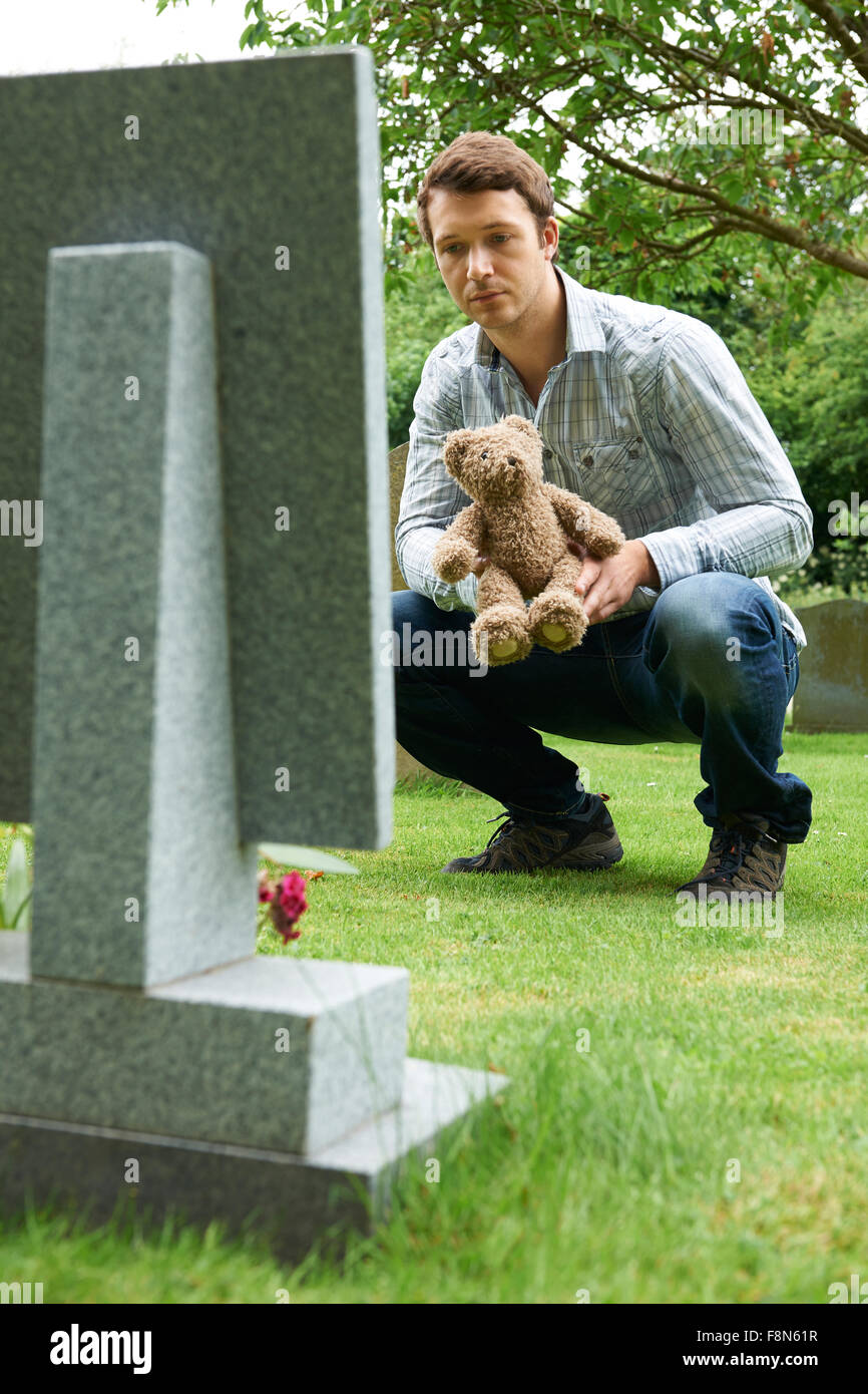 Father Placing Teddy Bear On Child's Grave In Cemetery Stock Photo - Alamy
