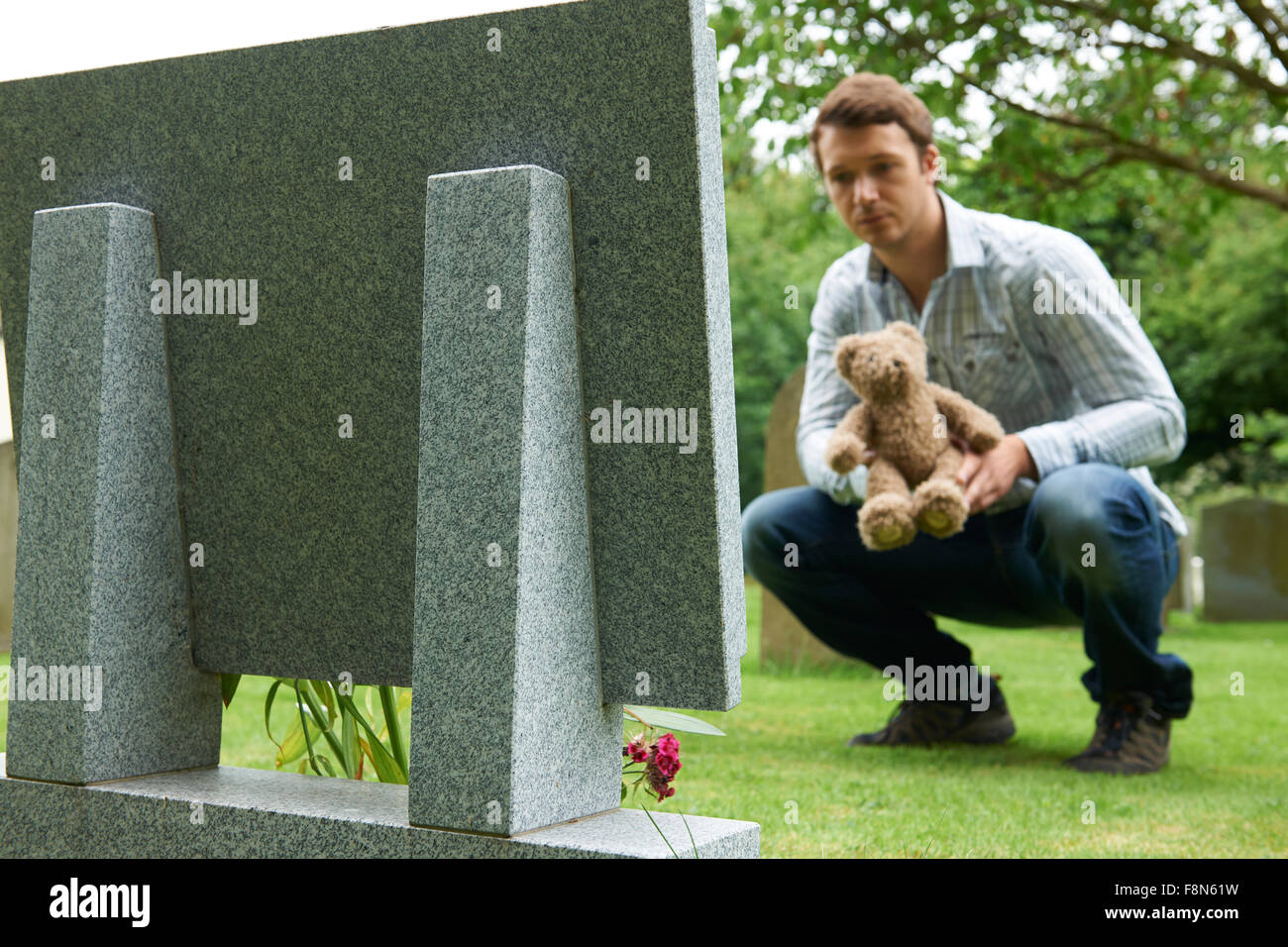 Father Placing Teddy Bear On Child's Grave In Cemetery Stock Photo - Alamy