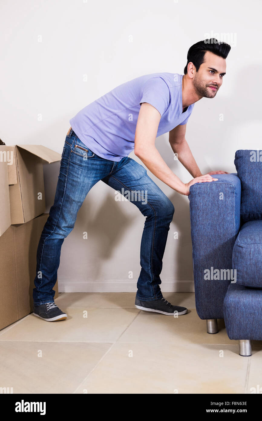 Man moving sofa in new home Stock Photo - Alamy