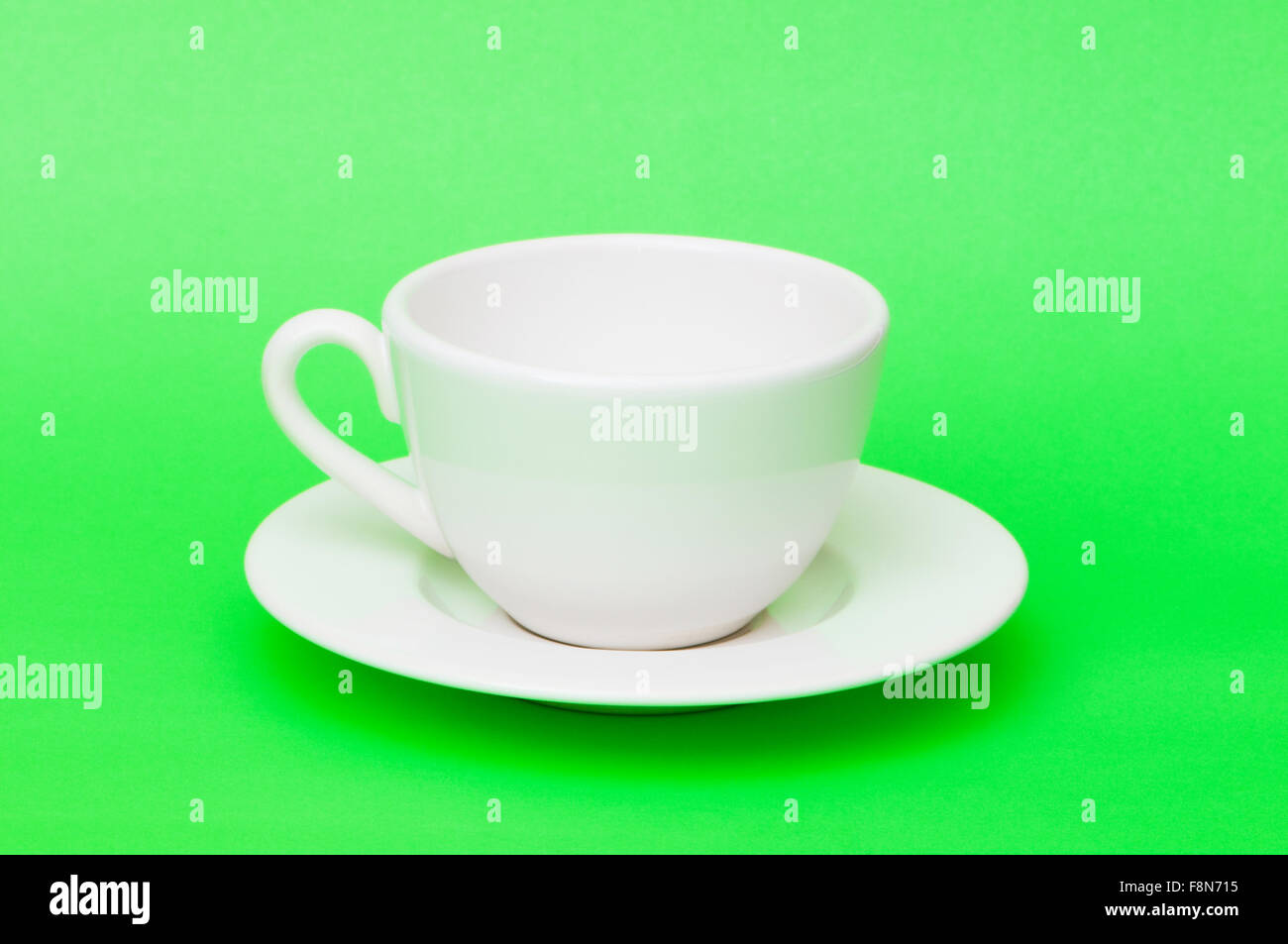 White tea cup isolated on green background Stock Photo - Alamy