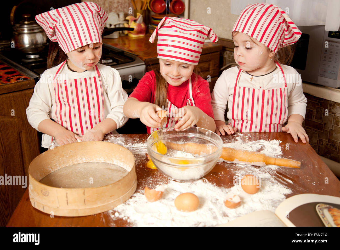 Three little chefs enjoying in the kitchen making big mess. Litt Stock ...