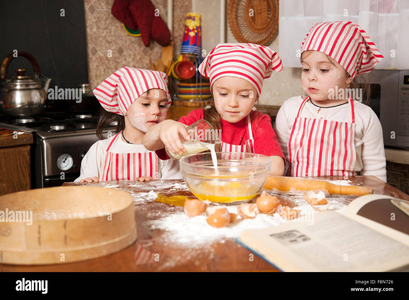 Three little chefs enjoying in the kitchen making big mess. Litt Stock ...