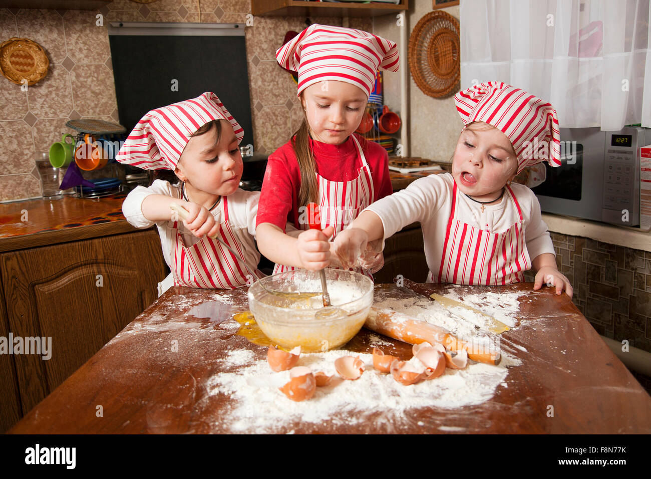 Three little chefs enjoying in the kitchen making big mess. Litt Stock ...