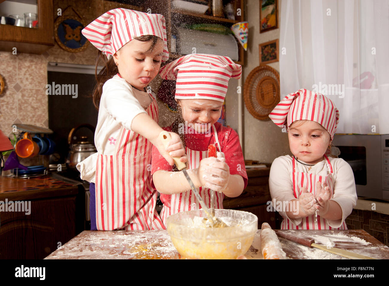 Three little chefs enjoying in the kitchen making big mess. Litt Stock ...