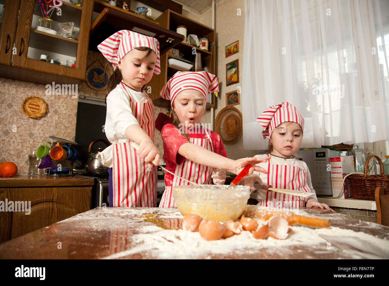 Three little chefs enjoying in the kitchen making big mess. Litt Stock ...