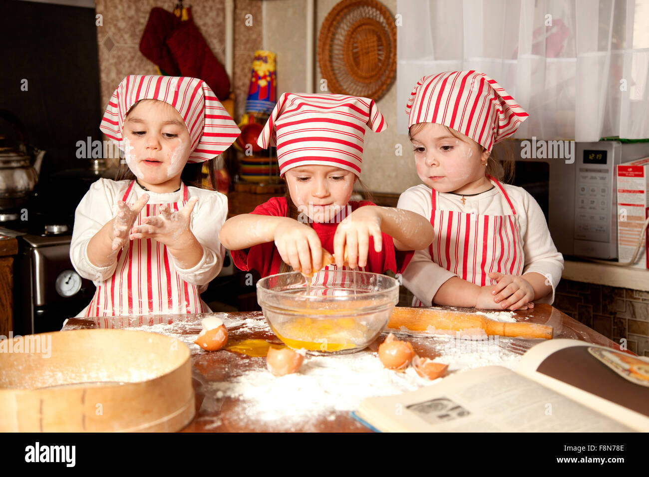Three little chefs enjoying in the kitchen making big mess. Litt Stock ...