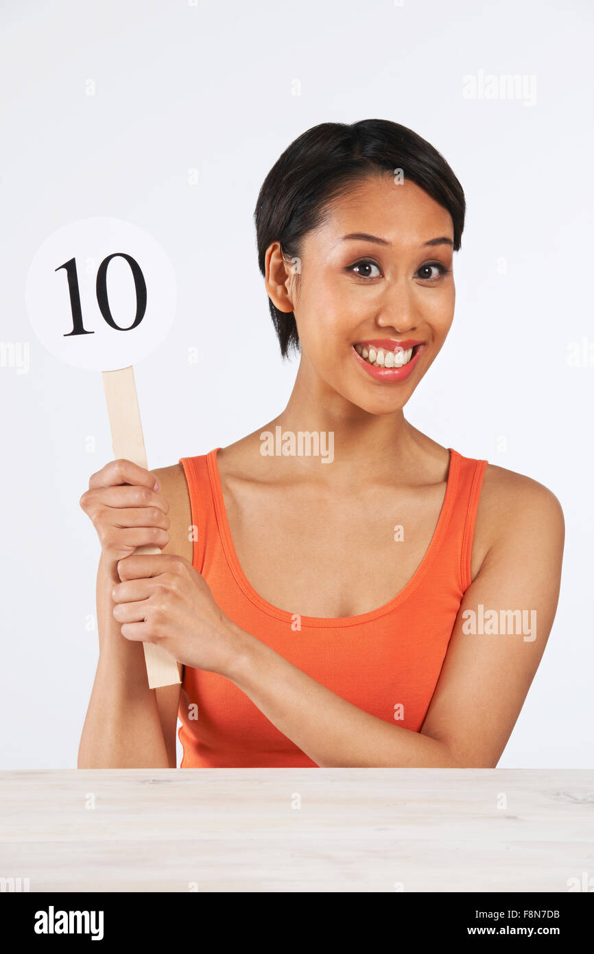 Happy Woman Holding Up Scorecard Giving Mark Out Of Ten Stock Photo - Alamy
