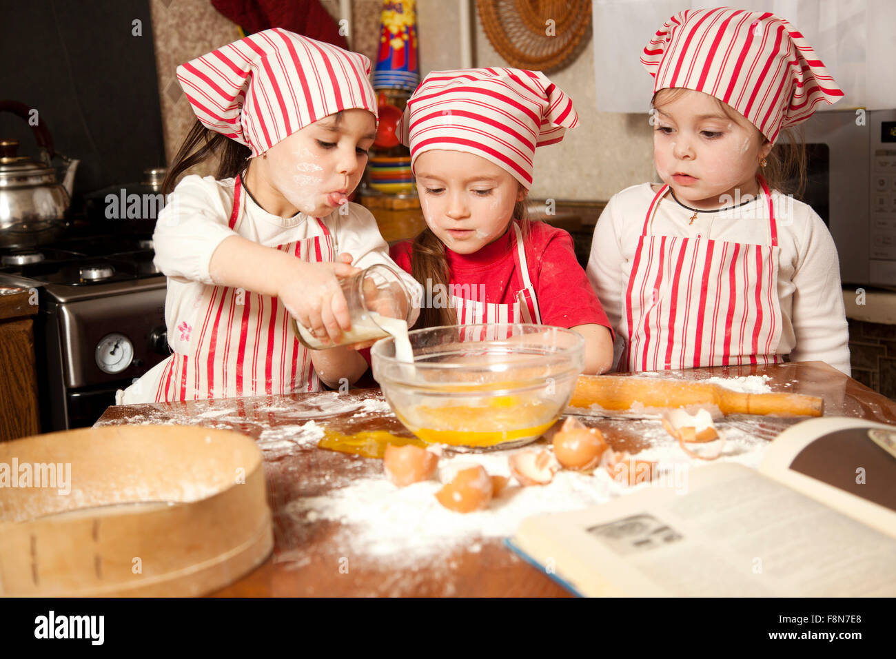 Three little chefs enjoying in the kitchen making big mess. Litt Stock ...