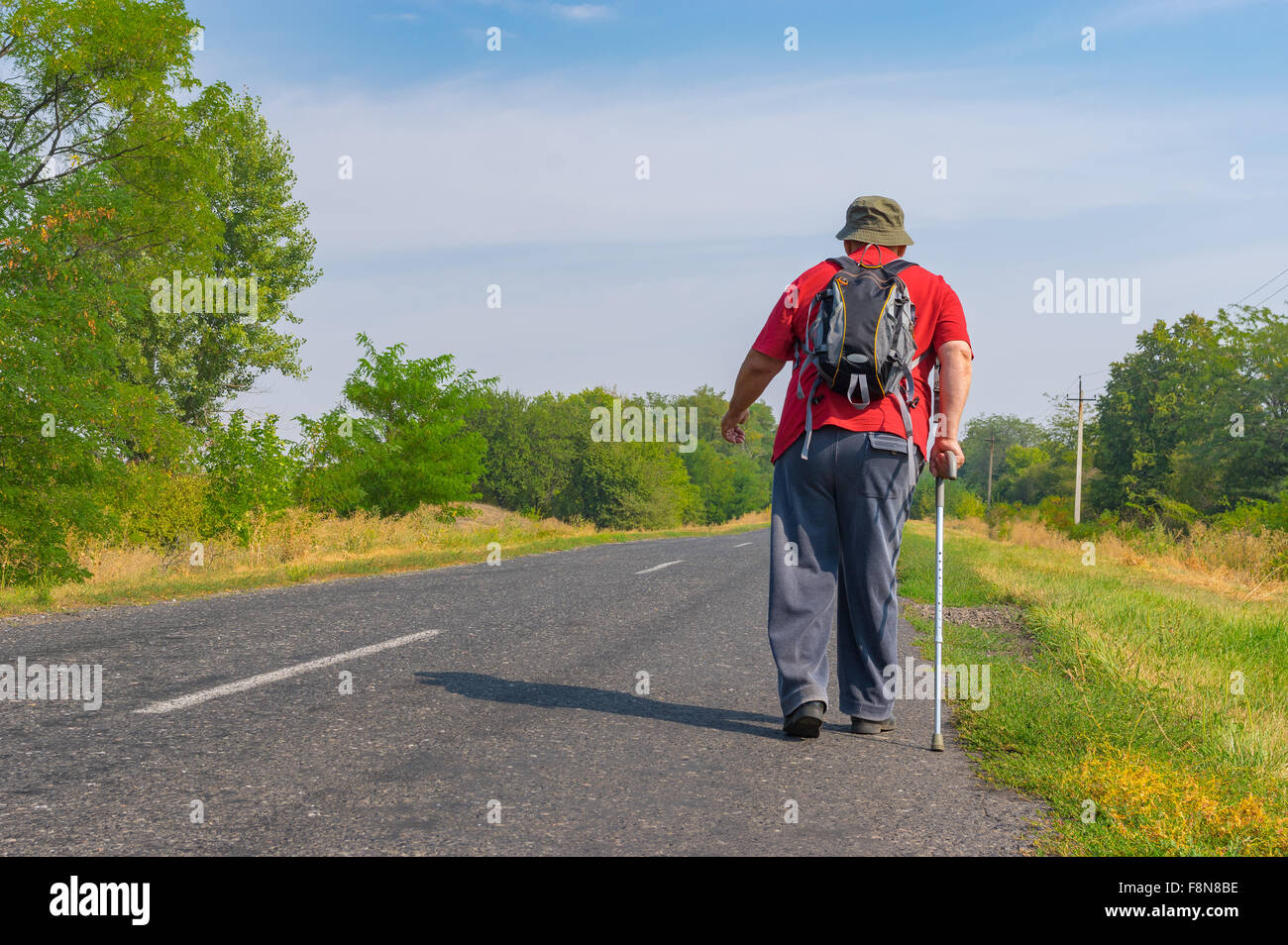 Elderly hiker walking on a roadside in Ukrainian rural area at summer ...