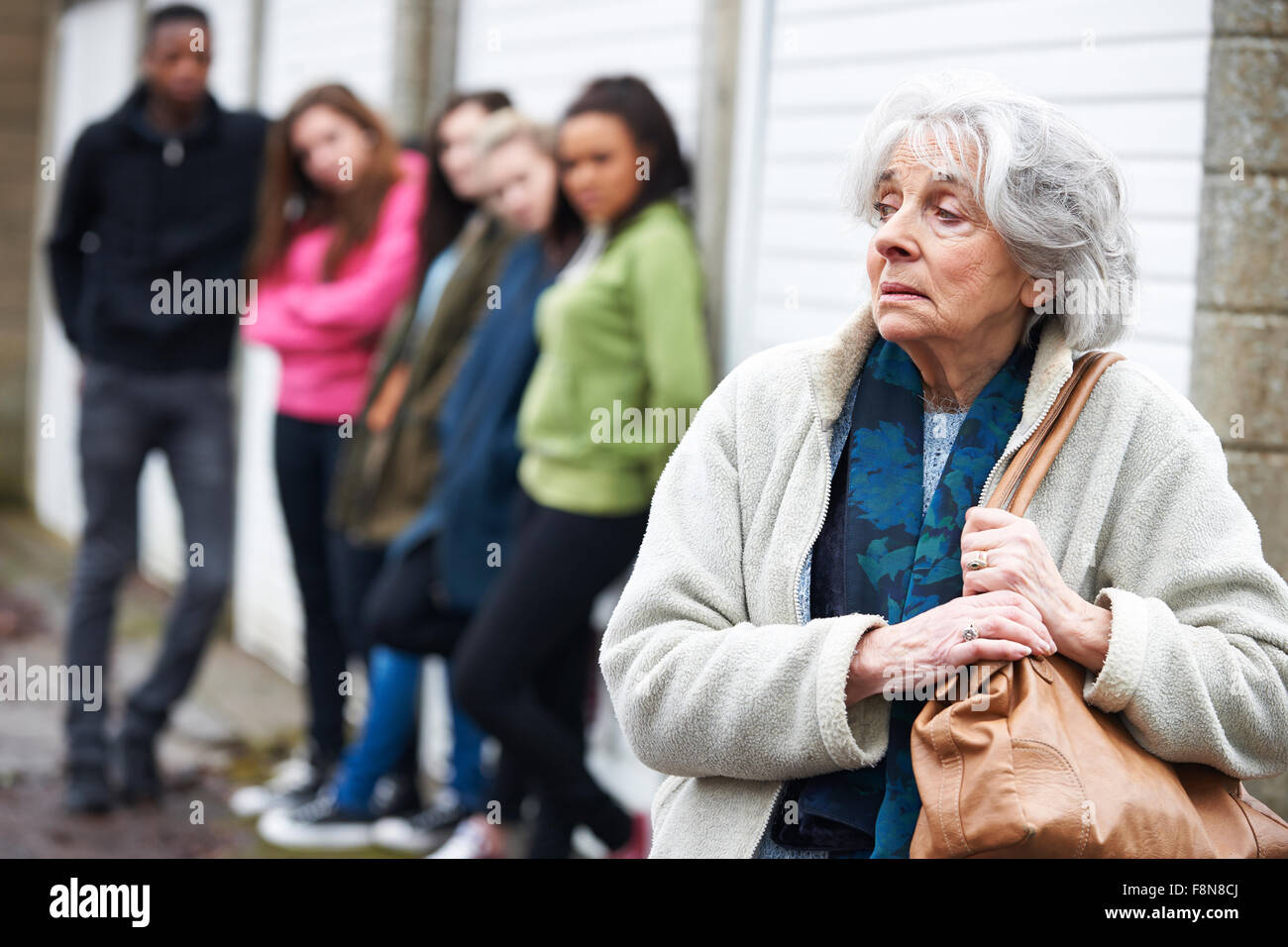 Senior Woman Feeling Intimidated By Group Of Young People Stock Photo ...