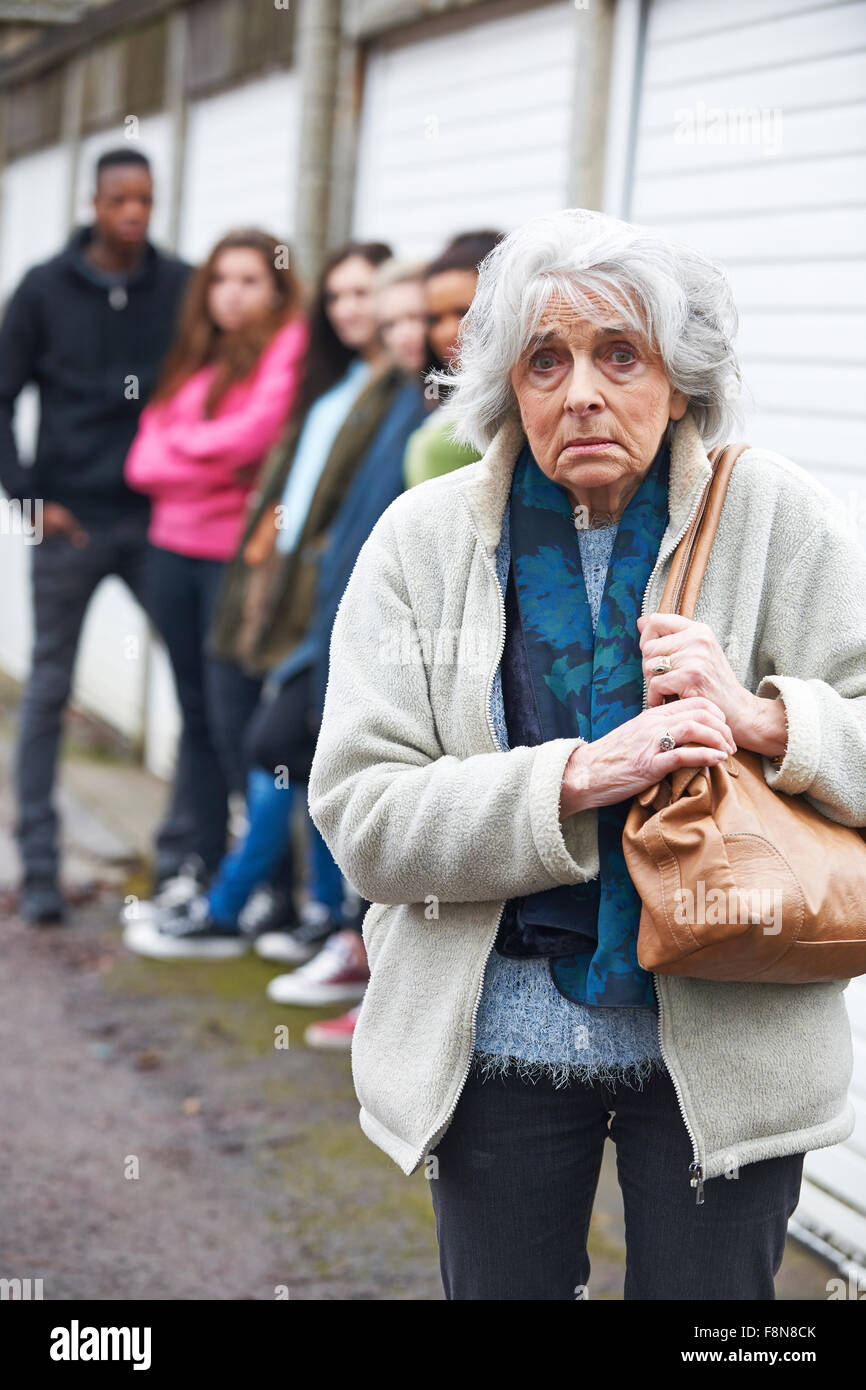 Senior Woman Feeling Intimidated By Group Of Young People Stock Photo ...