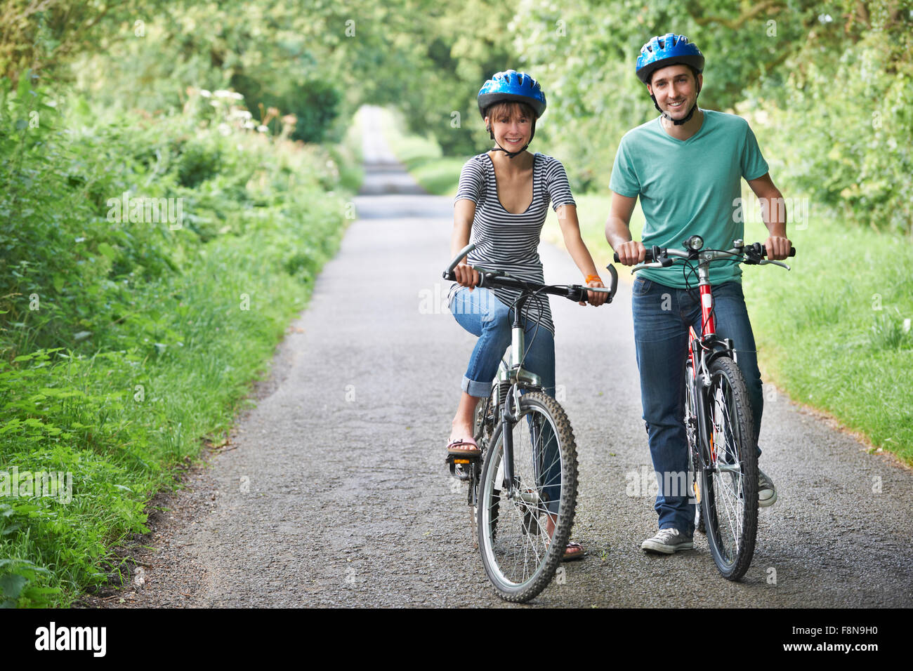Young Couple Cycling Along Country Road Stock Photo - Alamy