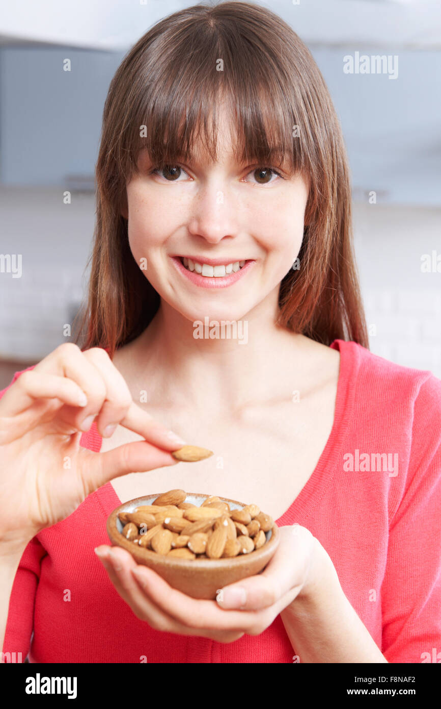 Young Woman Eating Almonds From Bowl Stock Photo - Alamy