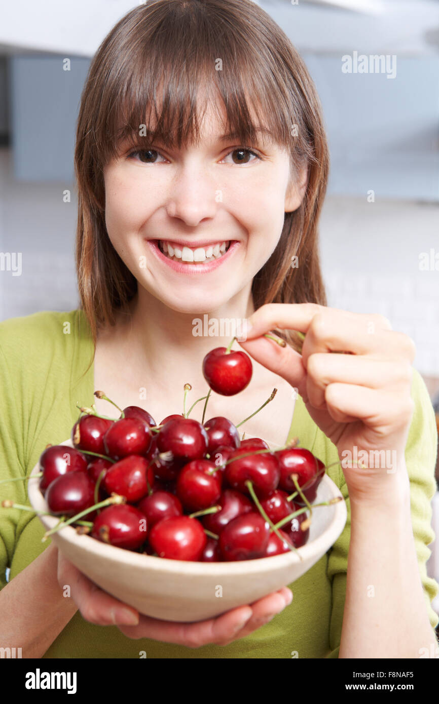 Young Woman Eating Cherries From Wooden Bowl Stock Photo - Alamy