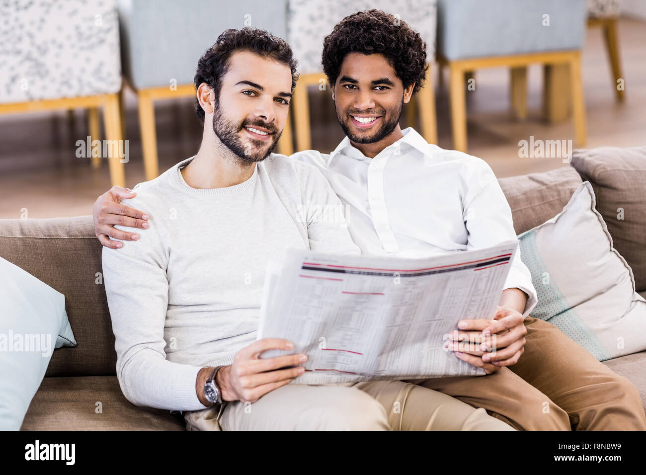 Happy gay couple reading newspaper Stock Photo - Alamy