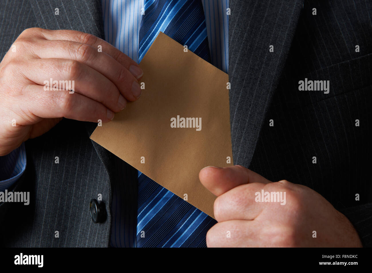 Businessman Putting Plain Brown Envelope In Jacket Pocket Stock Photo ...