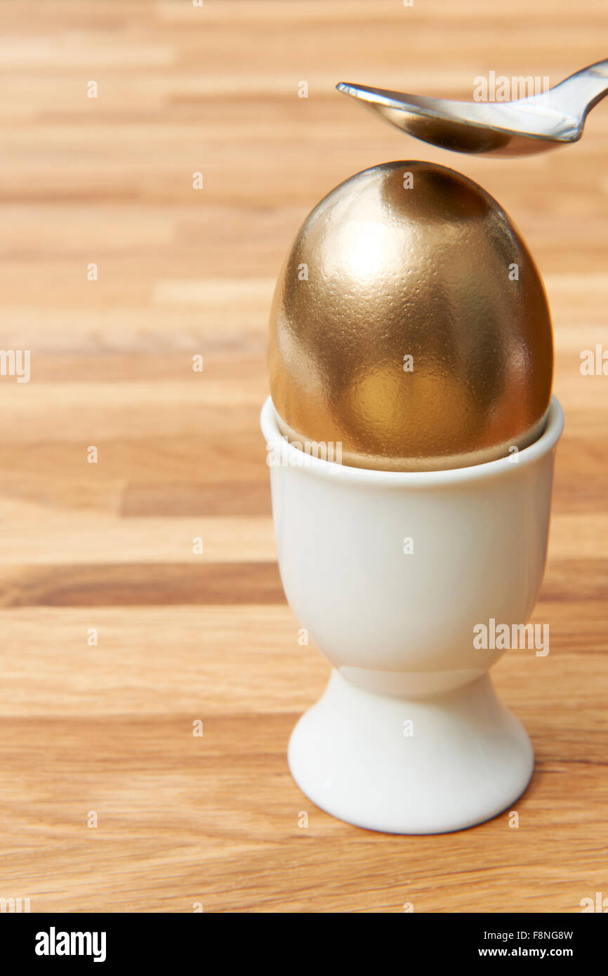 Spoon Cracking Golden Egg Stock Photo - Alamy