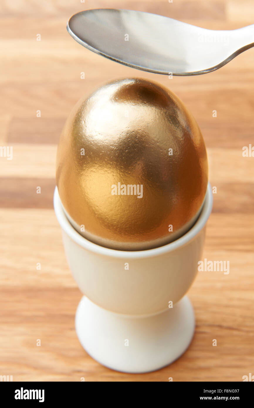 Spoon Cracking Golden Egg Stock Photo - Alamy