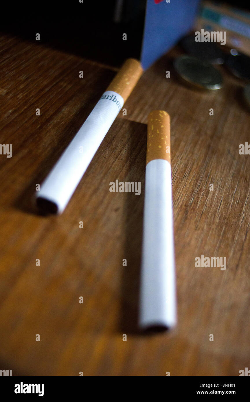 Two cigarettes on a wooden tabletop Stock Photo - Alamy