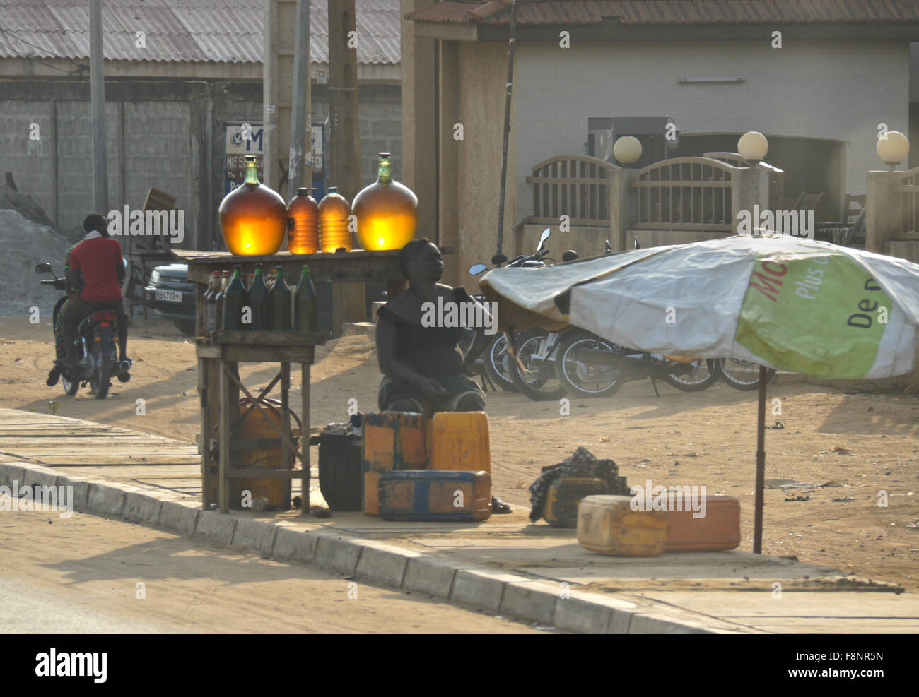 Woman selling gas (petrol, benzine) beside dusty highway, Porto Novo ...