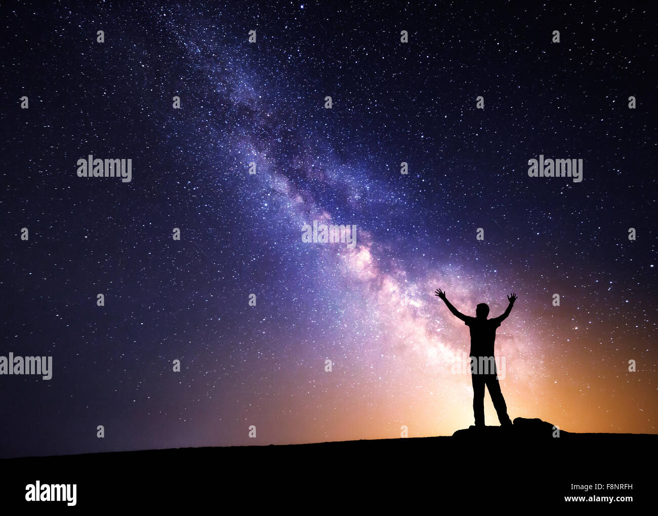 Milky Way. Night sky with stars and silhouette of a man with raised-up ...