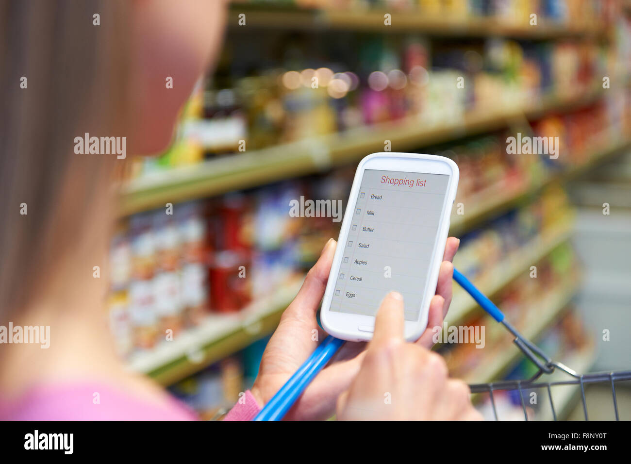 Woman Reading Shopping List From Smartphone In Supermarkey Stock Photo ...
