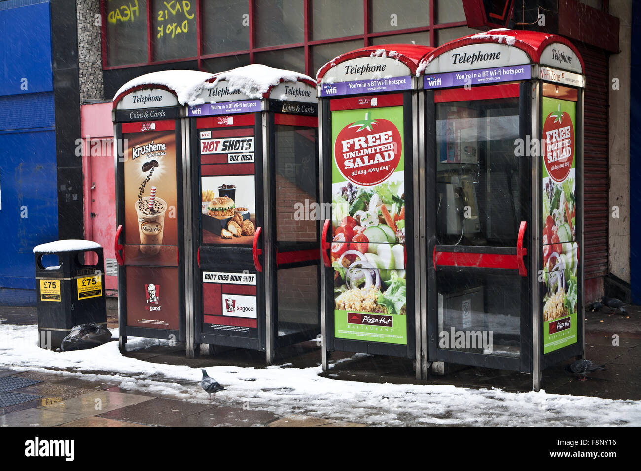 Four telephone boxes heavily covered in food advertising material ...