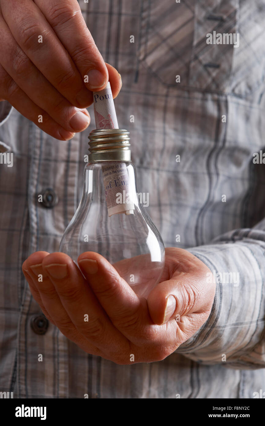 Man Putting Sterling Note Into Light Bulb Stock Photo - Alamy