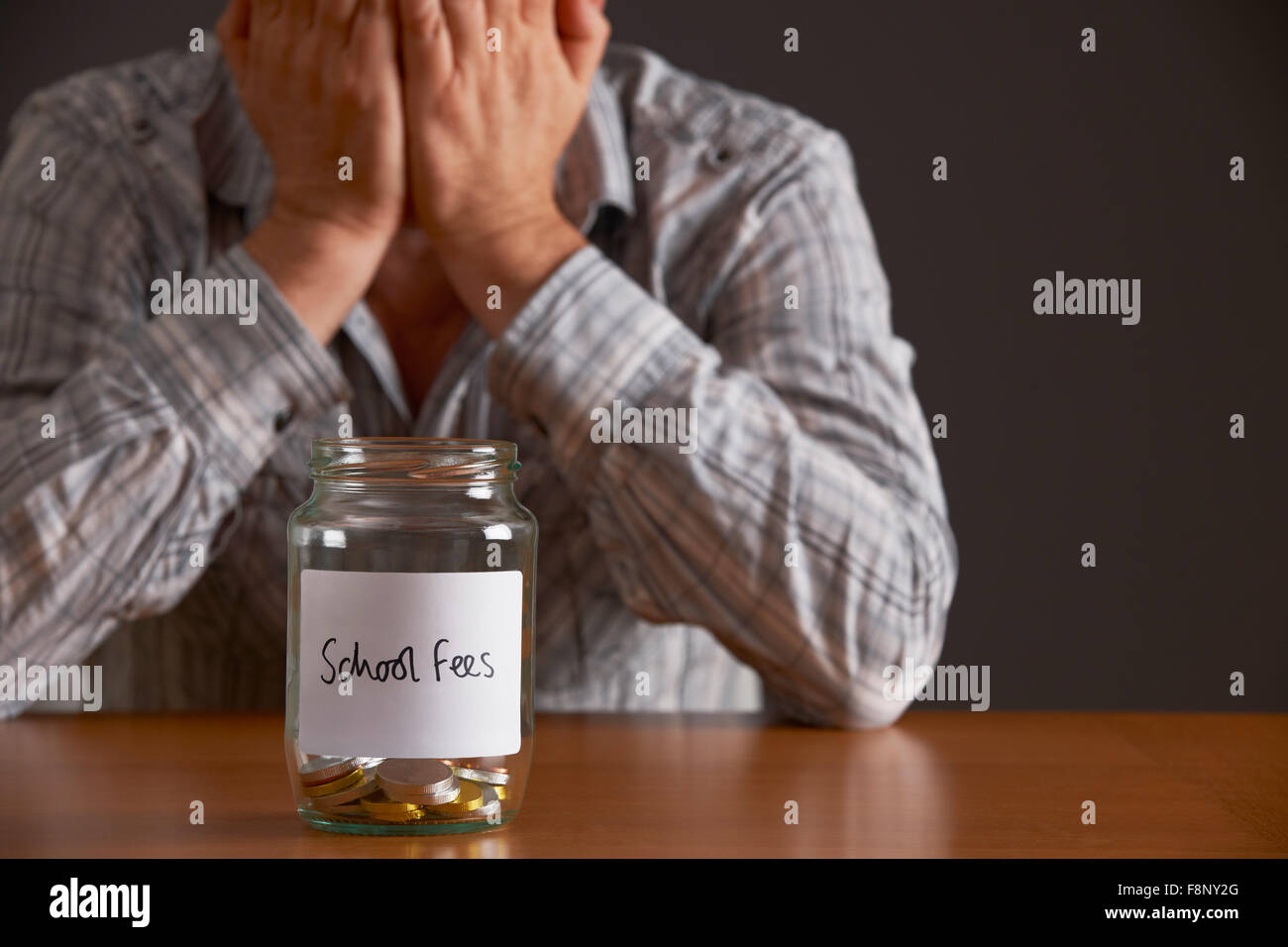 Man With Head In Hands Looking At Jar Labelled School Fees Stock Photo ...