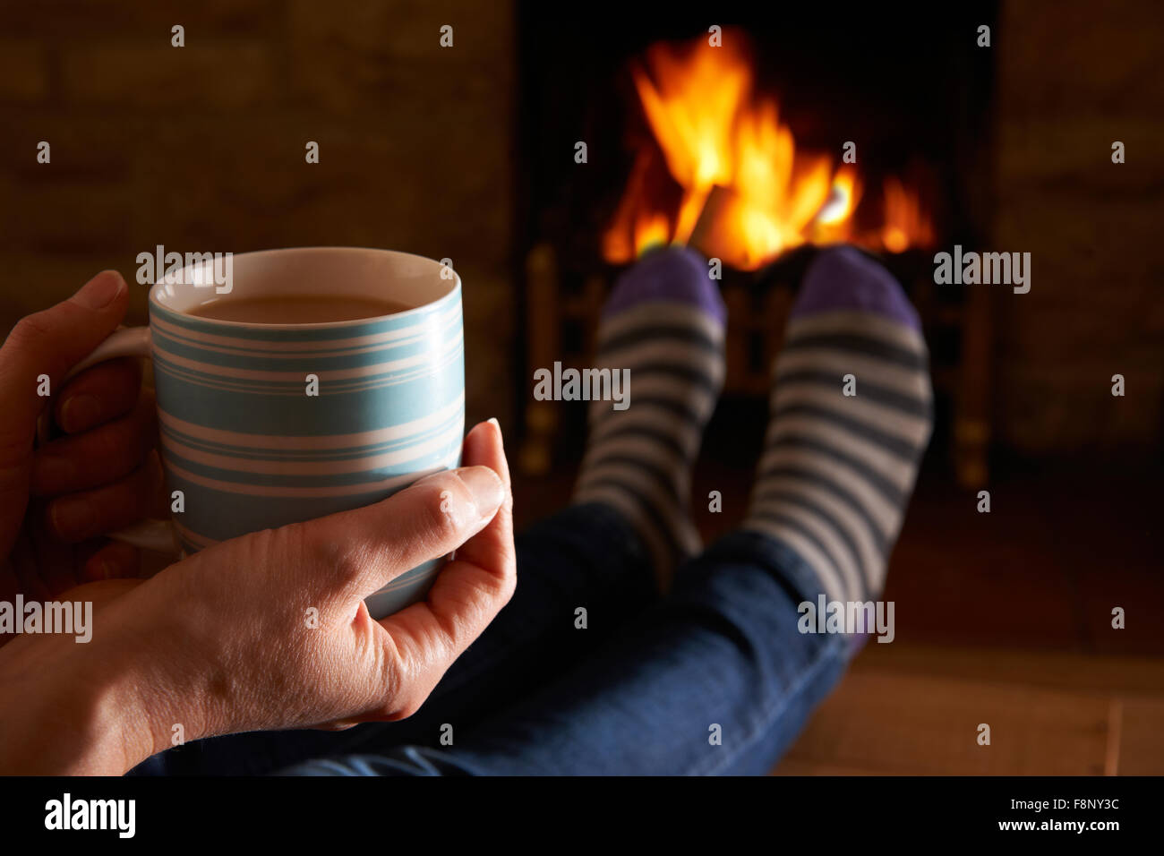 Woman With Hot Drink Relaxing By Fire Stock Photo - Alamy